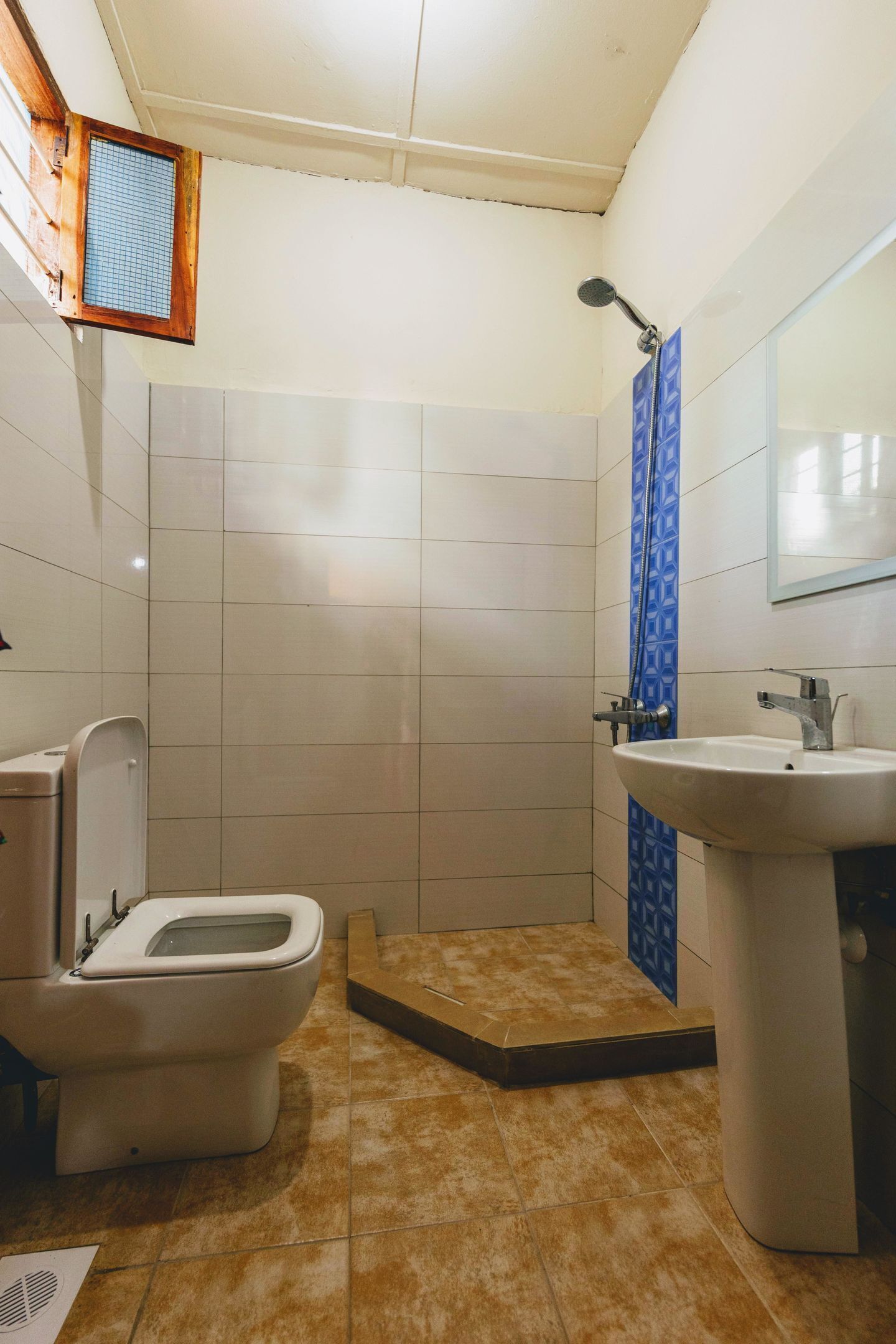 Casa de banho com sanita, lavatório e chuveiro.