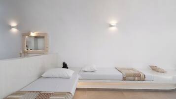Quarto minimalista com duas camas, um espelho e iluminação embutida na parede.