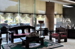 Um hall com sofá, cadeiras, mesa de centro e abajur.