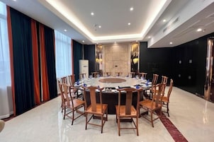 Sala de conferências com mesa redonda, cadeiras e quadro branco.