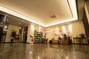 Um hall de hotel com uma mesa de recepção, área de estar e um painel com um mapa.