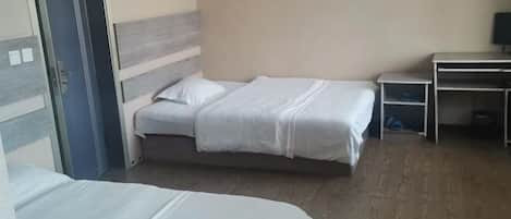Quarto de hotel com duas camas, uma escrivaninha e uma televisão.