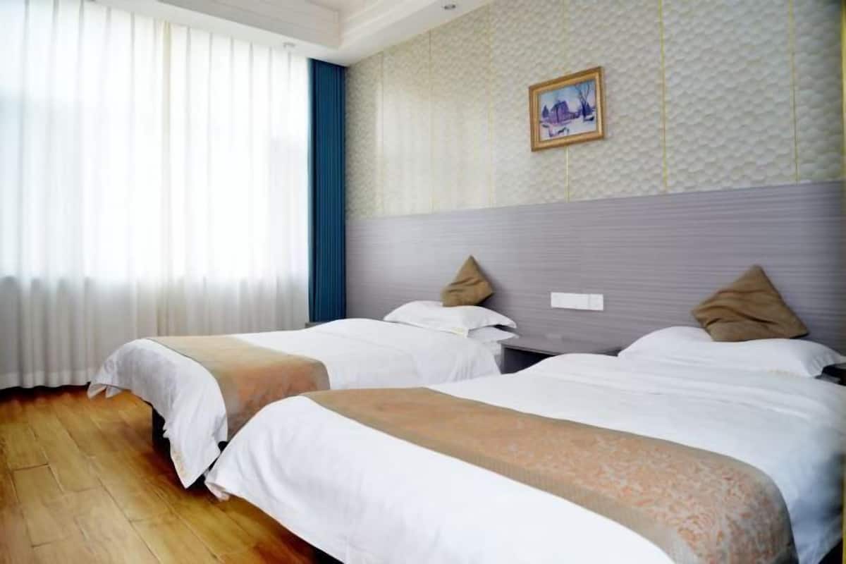 Quarto de hotel com duas camas, piso de madeira, parede estampada e um quadro emoldurado.