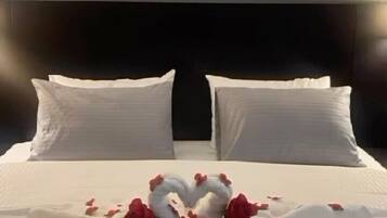 Cama bem arrumada com lençóis brancos e um arranjo decorativo de rosas e flores.