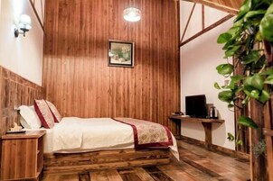 Quarto com painéis de madeira, uma cama, mesa de cabeceira e uma TV sobre suporte de madeira.