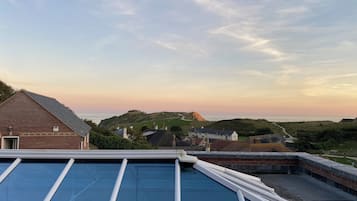 Um terraço no telhado com vista clara para o mar e colinas ao longe.