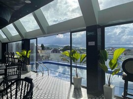 Uma área de piscina no terraço com vista para a cidade, plantas em vasos e mobiliário para área externa.