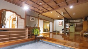 Um hall amplo com escada de madeira, balcão de recepção e um espelho grande.