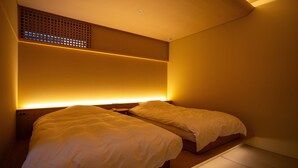 Quarto de hotel com duas camas, cabeceira de madeira e iluminação ambiente acolhedora.