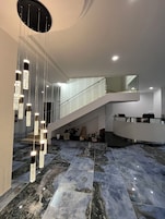 Um interior moderno com piso de mármore, uma escadaria e um balcão de recepção.