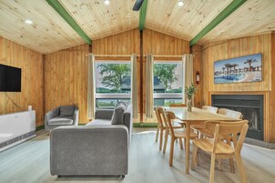 Um interior de madeira com área de jantar, sofás e lareira.