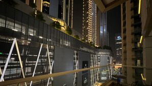 Interior moderno de hotel com varanda com vista para o horizonte urbano à noite.