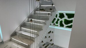 Uma escada moderna com guarda-corpos de vidro e plantas em vasos.