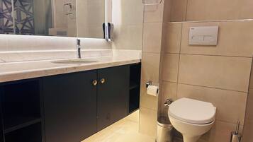 Uma casa de banho moderna com lavatório, sanita e um contentor de lixo.