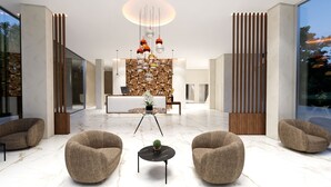 Um hall moderno com um balcão de recepção, duas áreas de estar circulares e uma parede decorativa com luminárias pendentes.