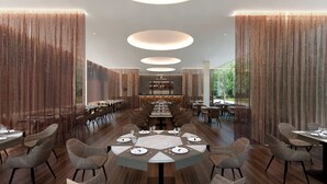 Um restaurante moderno com área de jantar central, várias mesas e um bar.