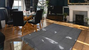 Uma sala de jantar com mesa de madeira, cadeiras pretas e um lustre.