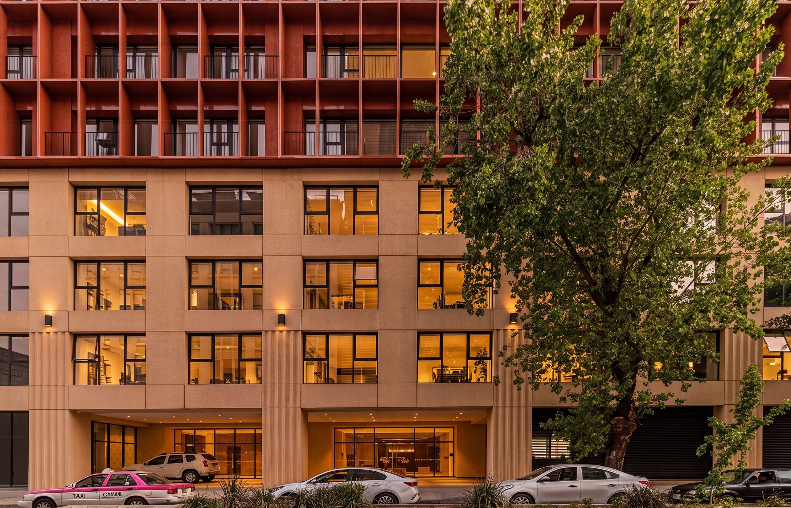 Um hotel com várias andares, fachada moderna, grandes janelas e uma árvore em primeiro plano.