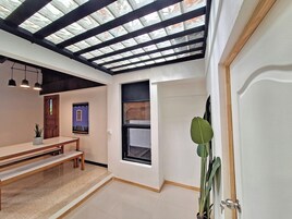 Um quarto com claraboia, um banco, uma planta em vaso e uma porta.