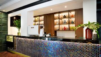 Cozinha moderna com bancada preta, máquina de café e exposição de objetos decorativos.