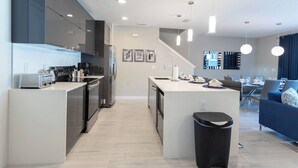 Uma cozinha moderna com uma ilha central, eletrodomésticos embutidos e iluminação pendente.