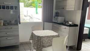 Uma cozinha compacta com mesa e cadeiras, micro-ondas e armários.