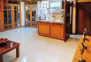 Um hall de hotel com balcão de recepção, armários de madeira e piso de azulejos.