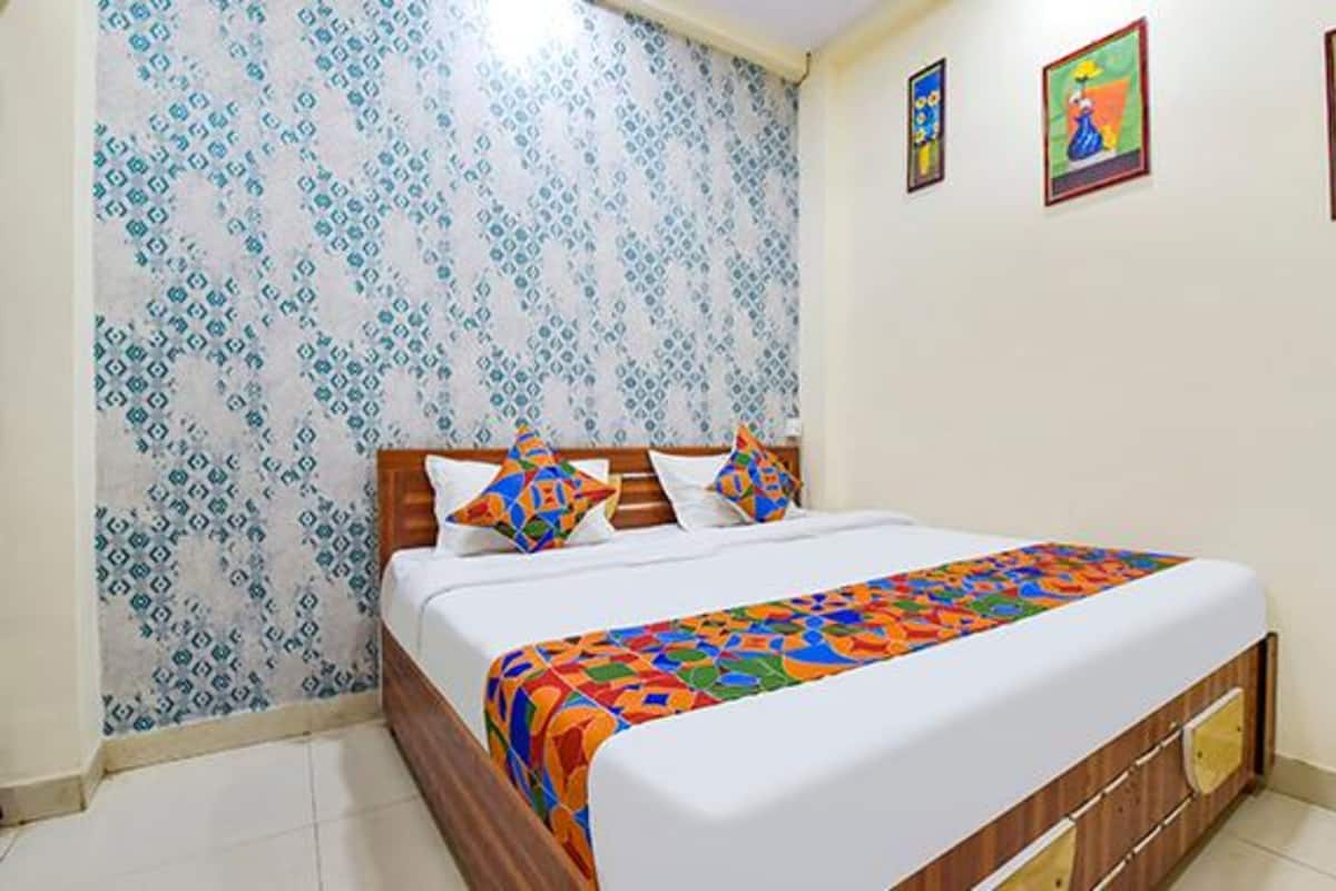 Quarto com papel de parede estampado, estrutura de cama de madeira e colcha colorida.