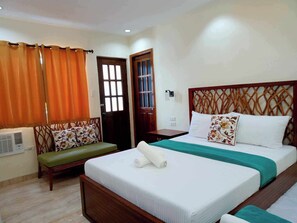 Quarto de hotel com uma cama, um banco e uma porta.