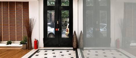 Entrada de hotel moderna com porta preta, piso de azulejos e painel de madeira ripa.