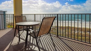 Varanda com mesa e cadeiras com vista para a praia.