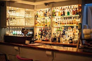 Uma área de bar com prateleiras de garrafas de bebidas e copos.