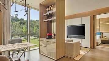 Uma sala de estar moderna com televisão de tela plana, área de jantar e vista para o exterior.