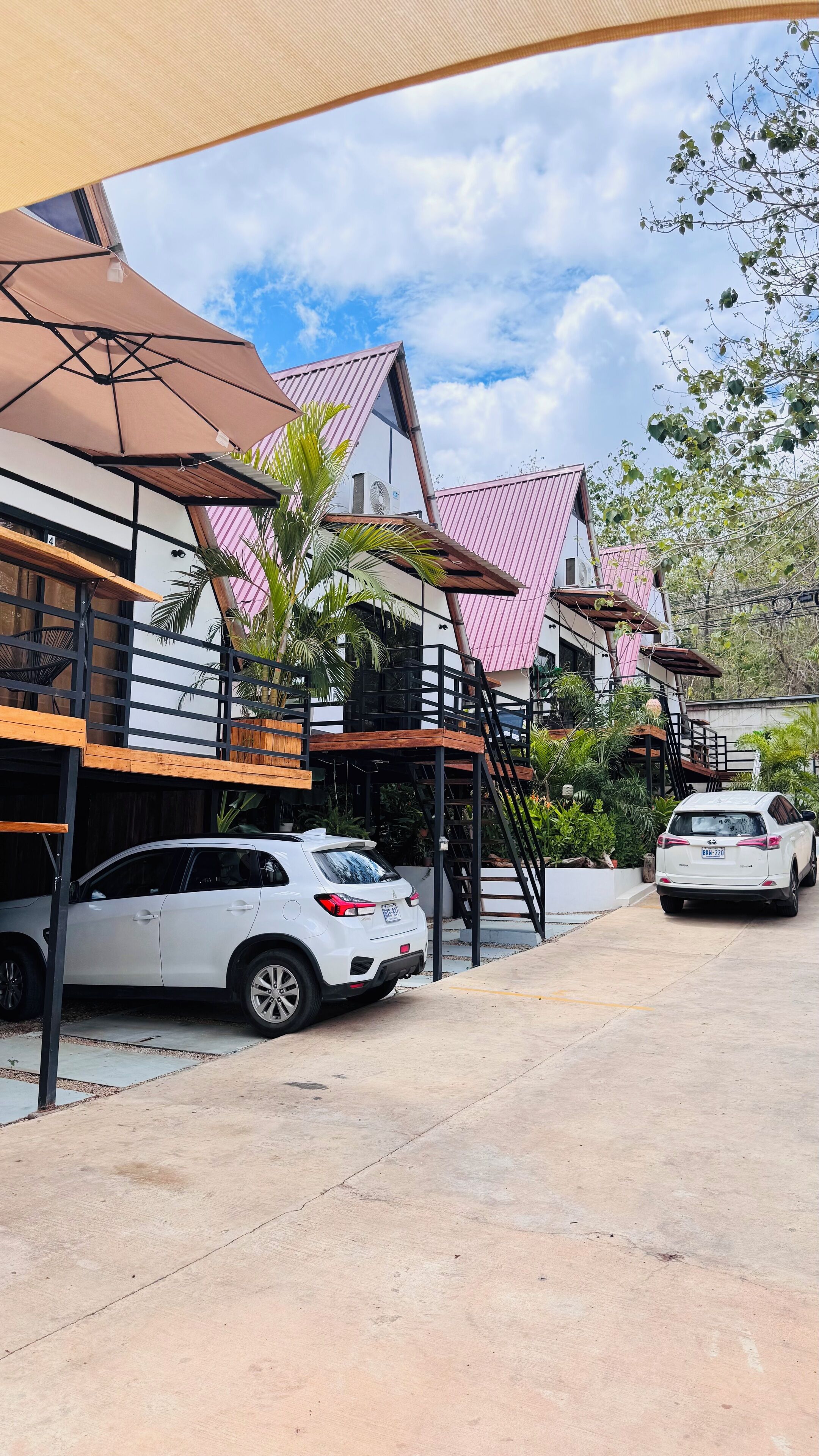 Zona residencial com casas de dois andares, uma garagem coberta e um carro branco estacionado na frente.