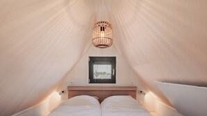Quarto com duas camas, cabeceira de madeira, luminárias de cabeceira, janela com persianas e luminária pendente.