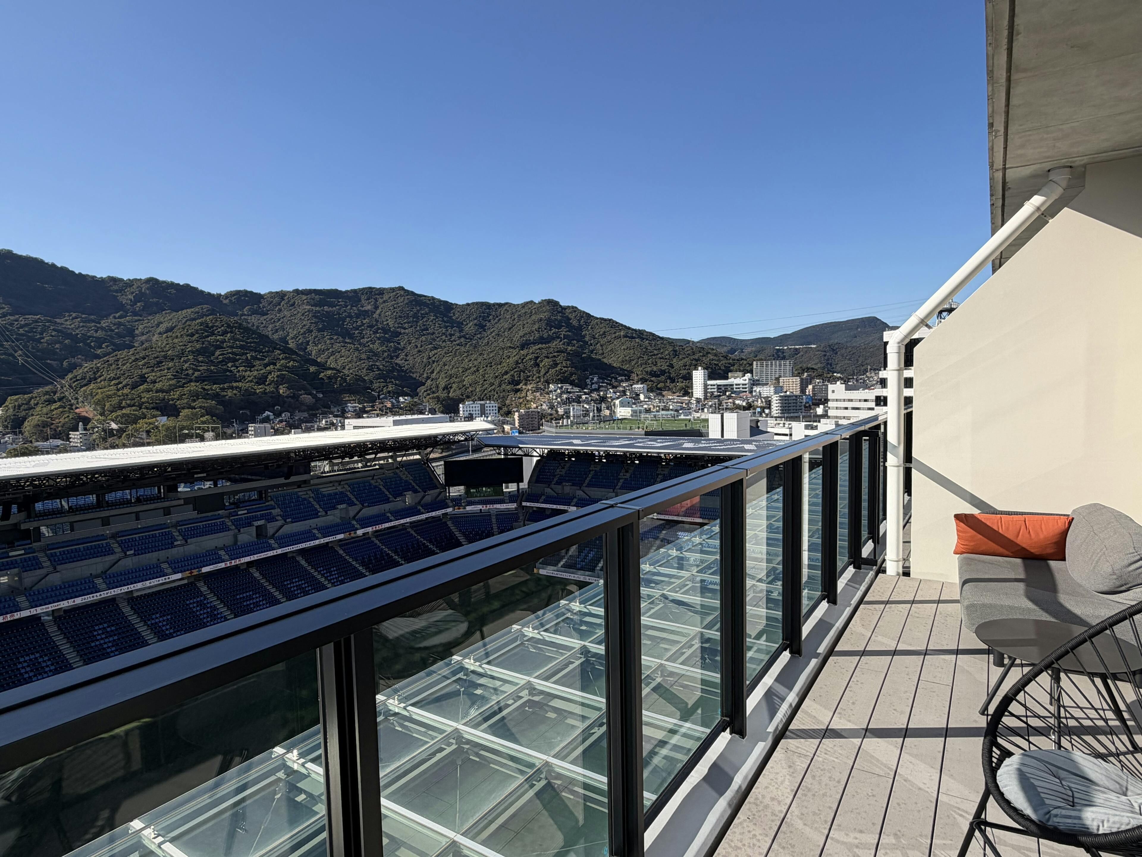 Uma varanda com vista para um estádio e montanhas.