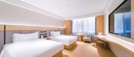 Quarto de hotel com duas camas, uma escrivaninha, uma cadeira e uma janela grande.