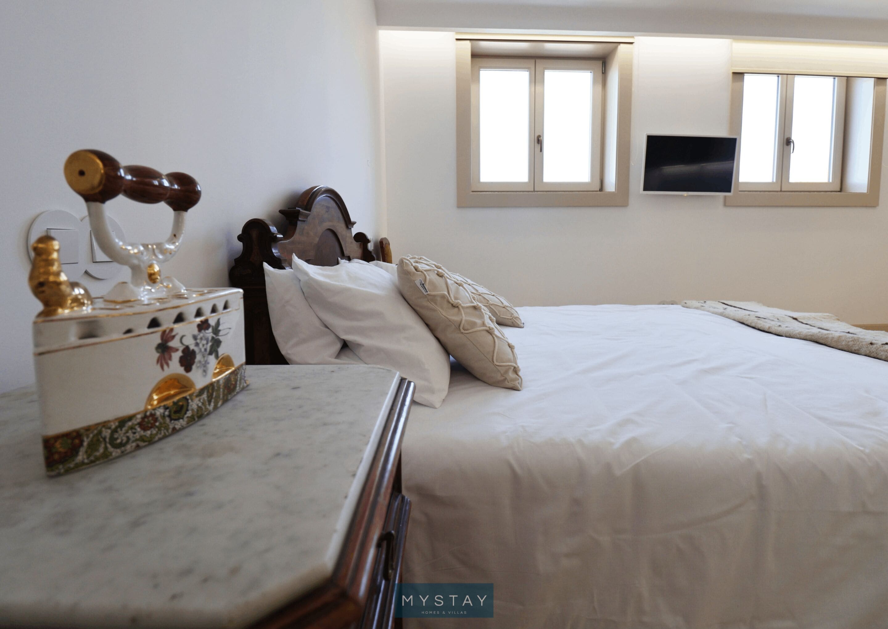 Quarto com cama, mesa de cabeceira, cômoda e janela com persianas.