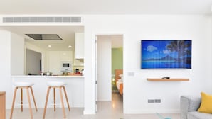 Uma sala de estar moderna com um sofá, uma mesa de centro e uma TV fixada na parede.