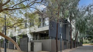 Um edifício moderno com telhado plano, janelas amplas e área externa coberta.