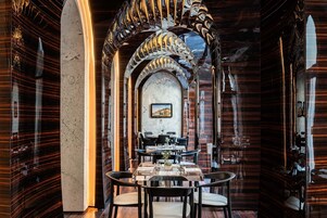 Uma área de refeições com uma mesa comprida, cadeiras e um arco central.