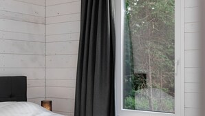 Quarto com cama, janela e mesa de cabeceira.