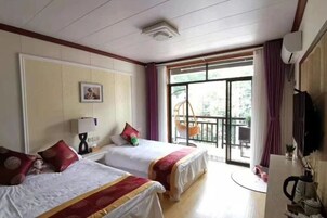 Quarto de hotel com duas camas, varanda, televisão e uma pequena mesa com chaleira.