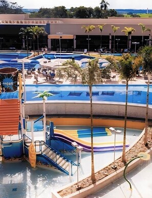 Parque aquático com várias piscinas, toboáguas e palmeiras.