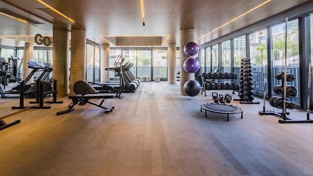 Uma academia com equipamentos de cardio, espaço para musculação e amplas janelas.