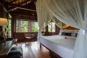Quarto com cama de dossel, mobiliário de madeira e amplas janelas com persianas.