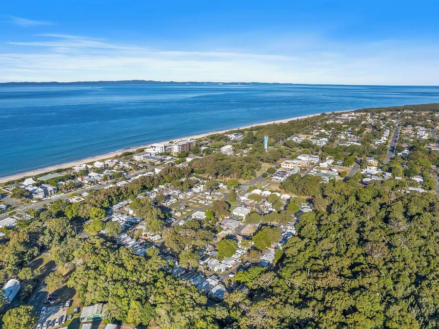 Vista aérea de uma cidade costeira com áreas residenciais, uma praia e uma grande extensão de água.