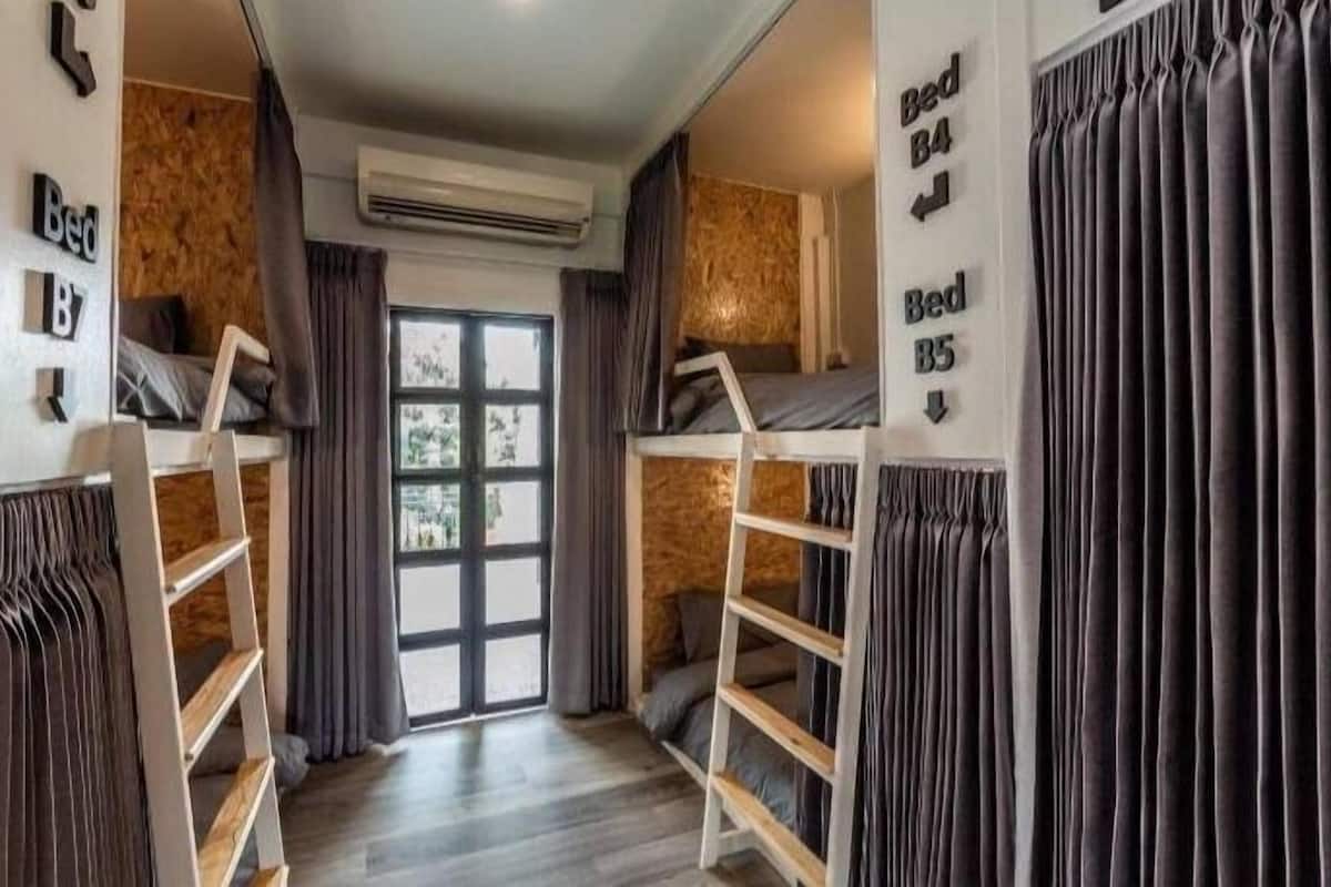 Quarto com beliches identificados como B4, B5 e B6, uma janela com cortinas e um ar condicionado na parede.