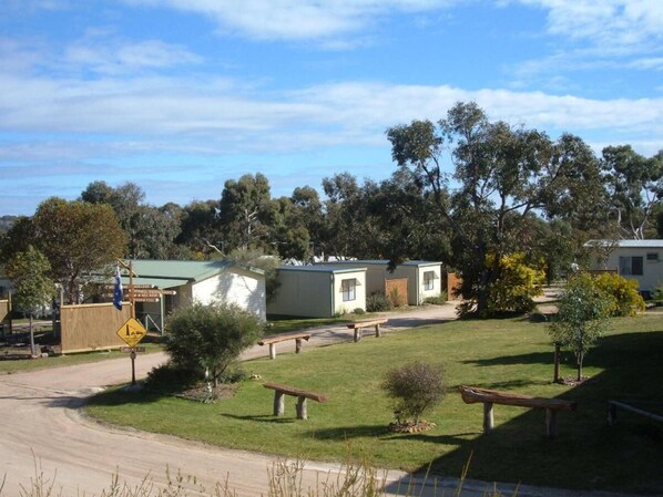 Um camping com casas móveis, mesas de piquenique e uma estrada de terra.