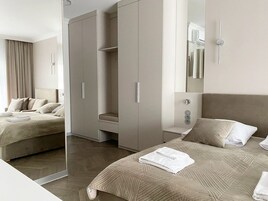 Quarto de hotel com duas camas, um guarda-roupa, um espelho e uma casa de banho.
